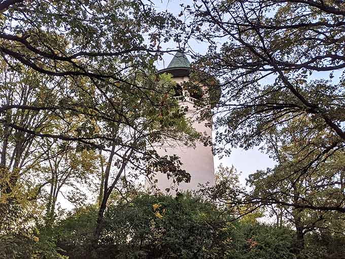 The tower plays peek-a-boo through autumn foliage, its distinctive green roof barely visible among nature's own colorful display.