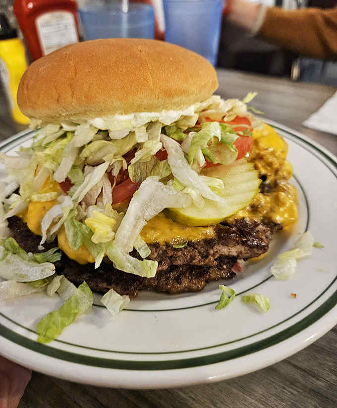 This isn't just a burger; it's a skyscraper of beef and toppings that requires both hands, several napkins, and possibly an engineering degree.