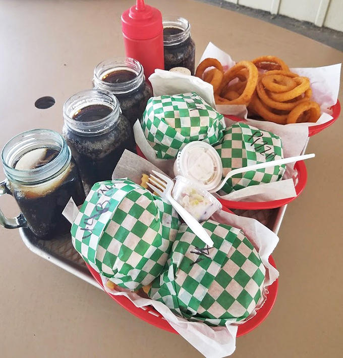 A feast for the senses: checkered-wrapped burgers nestled beside golden onion rings and root beer served in frosty mason jars.