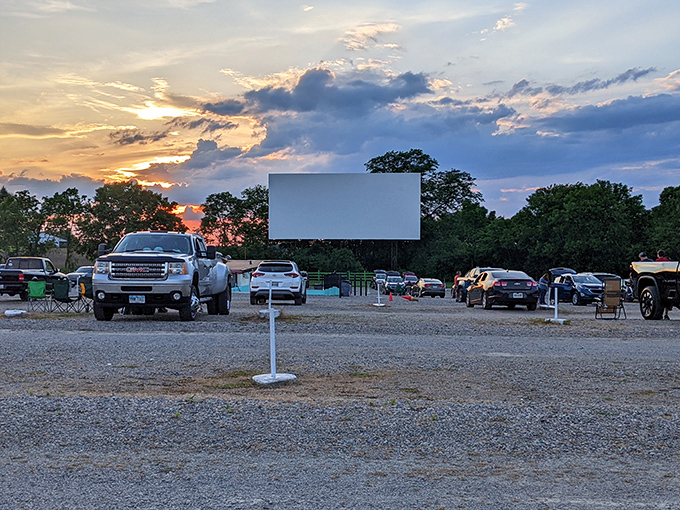 Holiday Auto Theatre's screen awaits the darkness as cars settle in for an evening of entertainment. That sunset creates the perfect mood for outdoor movie magic.