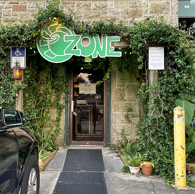 O'Zone Pizza Pub's entrance blends into its stone facade, with lush greenery softening the former bomb shelter's industrial exterior.