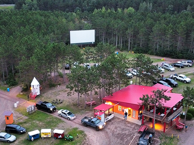 An aerial view of Stardust Drive-In shows the bright red concession building and carefully arranged viewing area surrounded by Wisconsin's beautiful pine forests.