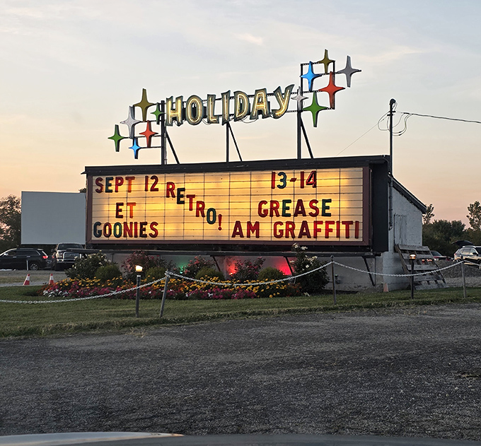 Holiday Auto Theatre's illuminated sign announces a retro movie weekend featuring classics like The Goonies and Grease. Those colorful stars on top are pure 1950s nostalgia!