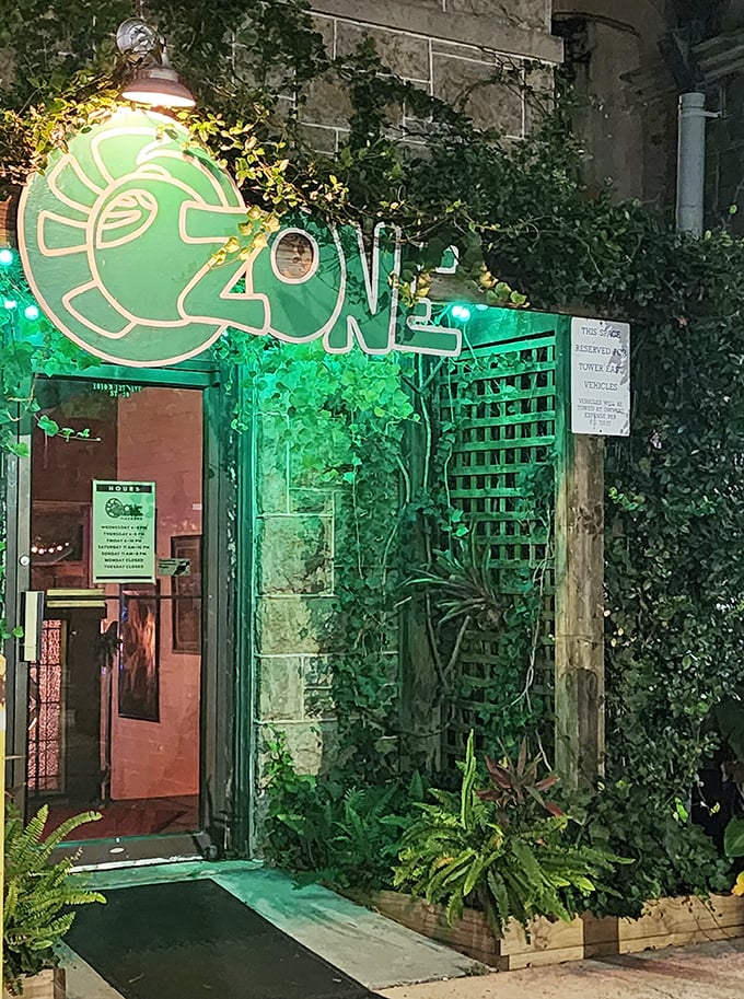 Evening transforms O'Zone Pizza Pub with emerald lighting highlighting its unique entrance. The converted bomb shelter offers both history and delicious pizza.