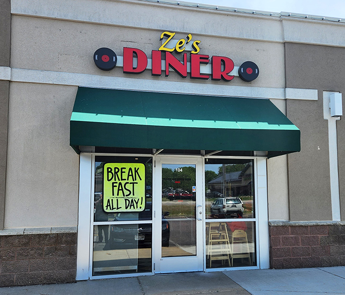 The welcoming entrance of Ze's Diner features their signature green awning and retro signage that beckons hungry patrons inside.