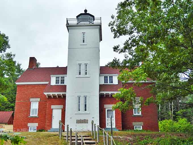 The 40 Mile Point Lighthouse stands sentinel against time and tide, its red-roofed keeper's house telling tales of maritime history.