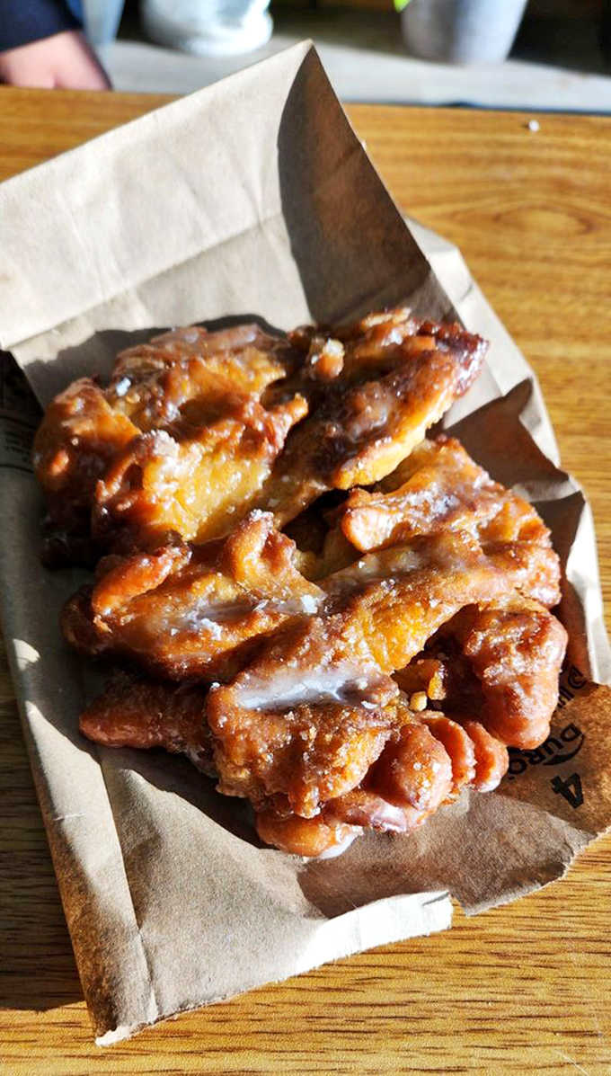 That apple fritter looks like it could double as a small pillow, golden and twisted with cinnamon-sugar goodness that demands immediate attention and possibly a fork.