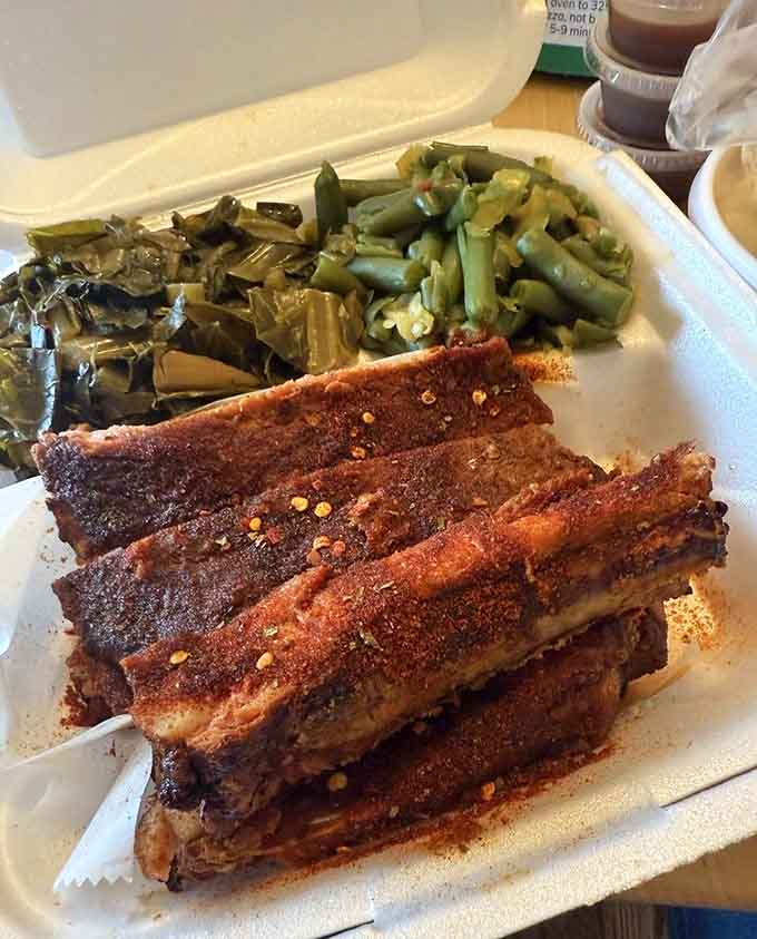 That half slab of ribs flanked by collard greens and green beans is basically a love letter to traditional barbecue, written in smoke and seasoning.