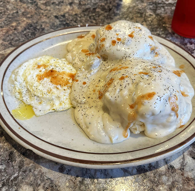 These aren't your average biscuits and gravy – they're cloud-like pillows drowning in peppery sausage gravy that could convert a vegan.