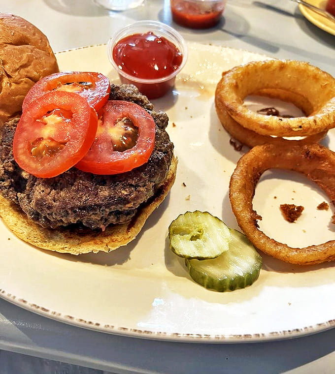 The Black Maria burger showcases the simple perfection of fresh tomatoes, crisp pickles, and a perfectly cooked patty on a golden bun.