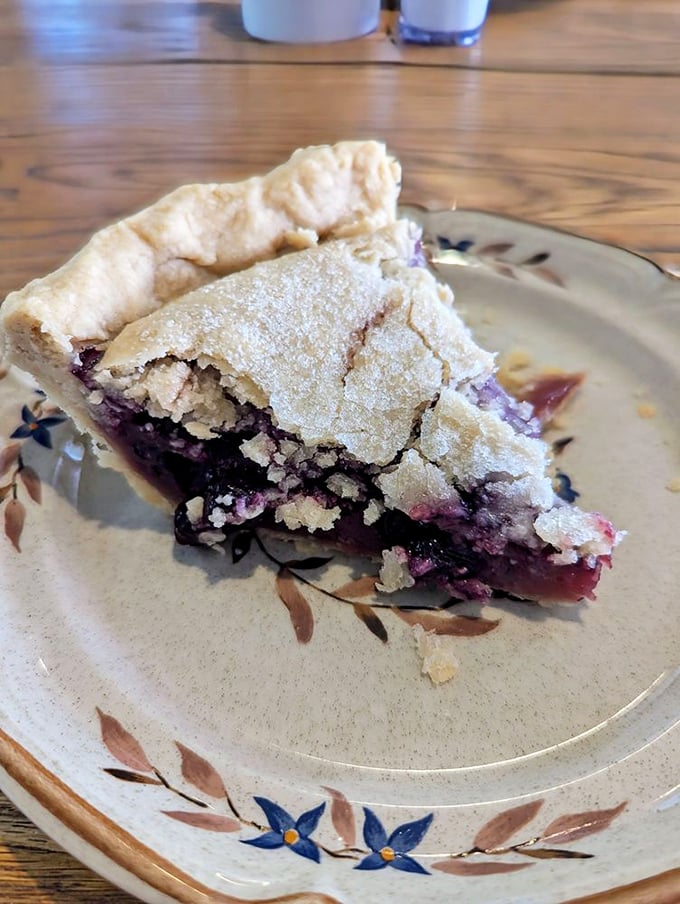 A slice of blueberry pie reveals its jewel-toned filling, the fruit's natural sweetness captured in a moment of pastry perfection.