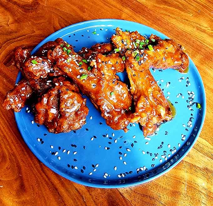 Wing perfection achieved! Sweet-spicy glazed chicken wings topped with sesame seeds and green onions disappear from plates with alarming speed.