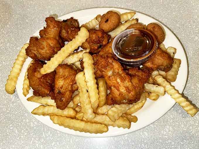 Golden-fried chicken wings nestled among crinkle-cut fries &ndash; comfort food perfection that doesn't need fancy presentation to make your taste buds stand at attention.