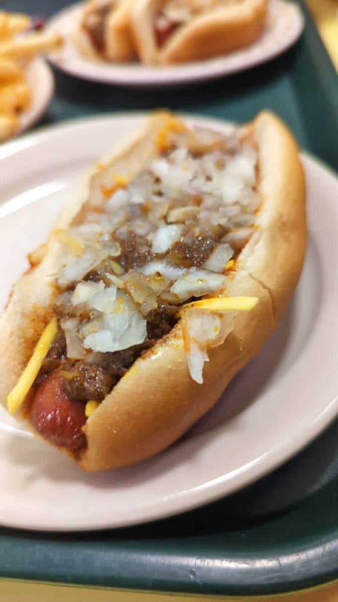 A proper Coney dog demands respect &ndash; a steamed bun cradling a beef frank, topped with house-made savory meat sauce and diced onions for that perfect texture contrast.