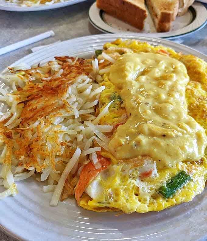 Fluffy egg perfection meets seafood luxury in this generous creation, with hash browns that deserve their own fan club.