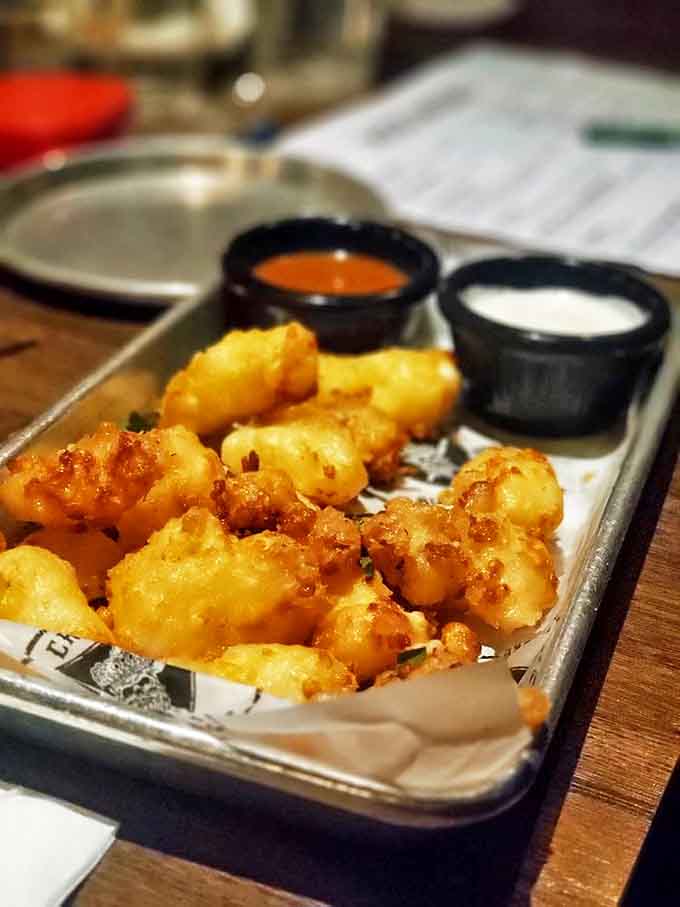 Golden cheese curds that crackle with promise, served with dipping sauces that make you question why anyone would eat cheese any other way.