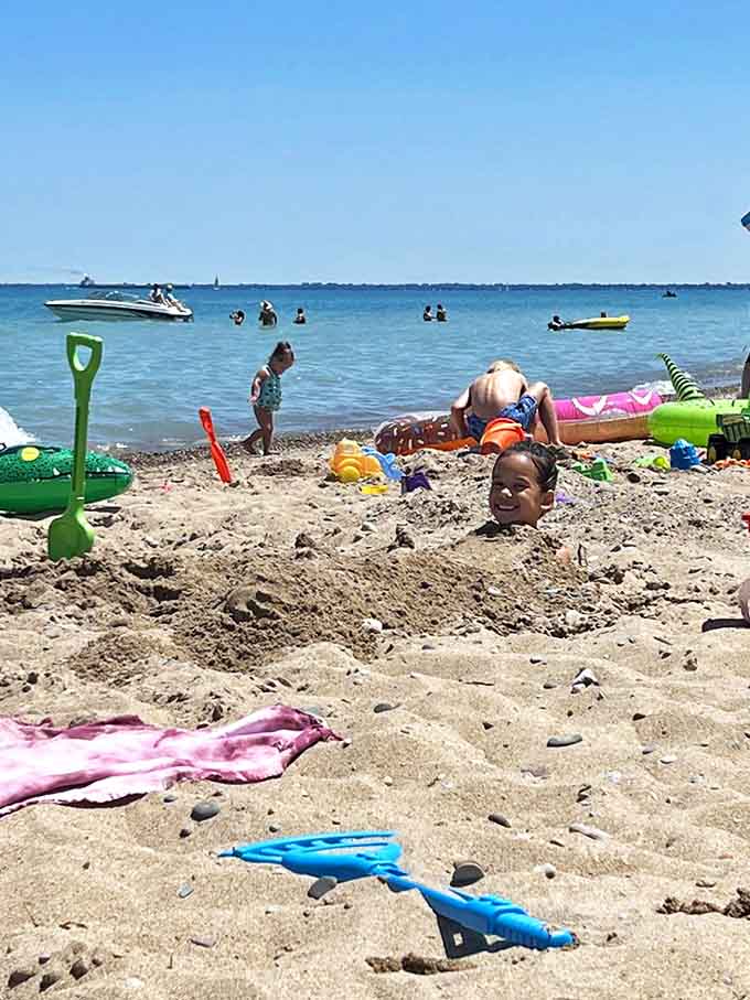 Childhood joy in its purest form &ndash; buried in sand with nothing but a smile peeking out, the universal sign of a perfect beach day.