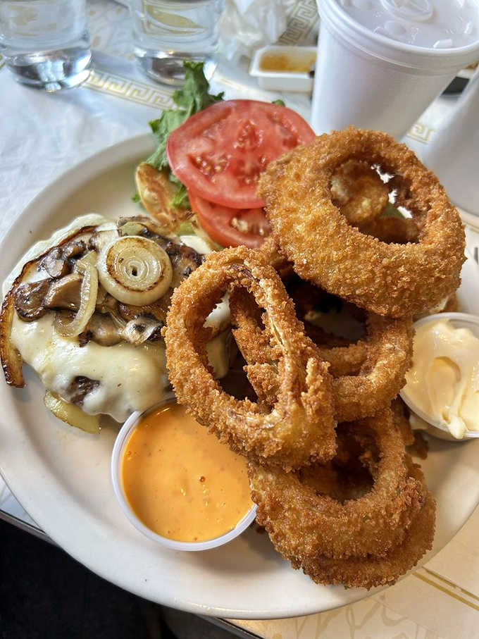 The Freddy Burger arrives like a beautiful, messy declaration of independence from diet culture – cheese melting, bacon glistening, onion rings standing guard.
