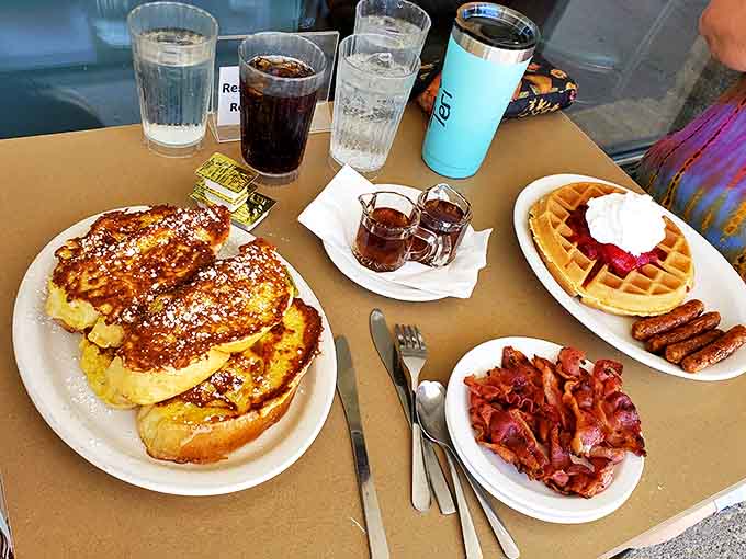 Sweet meets savory in this breakfast symphony—fluffy French toast dusted with powdered sugar alongside perfectly cooked bacon and a golden waffle with sausage.