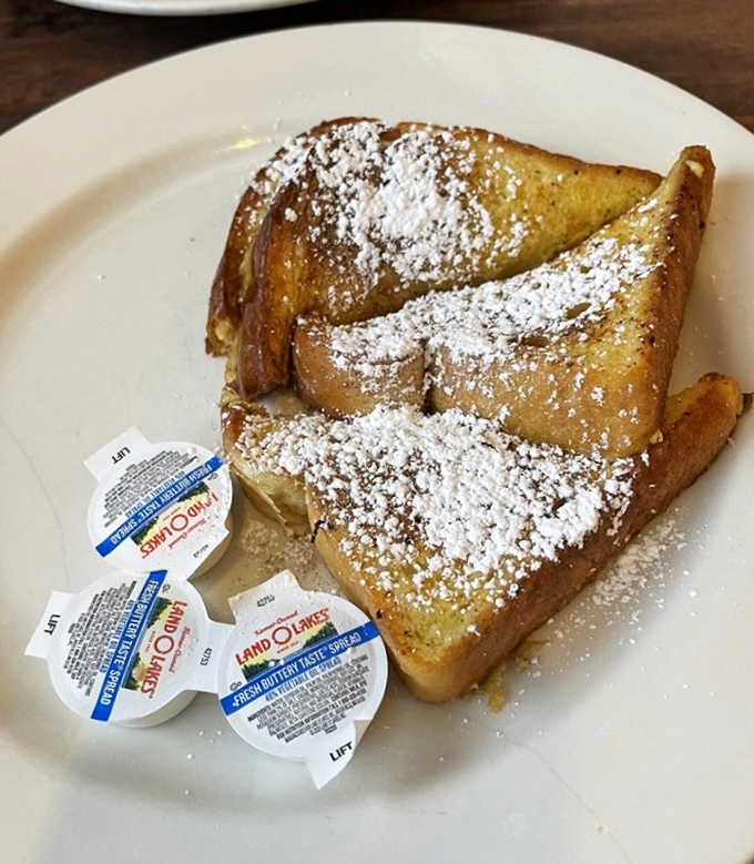 French toast that would make your grandmother jealous – golden, fluffy, and dusted with powdered sugar like fresh fallen snow.