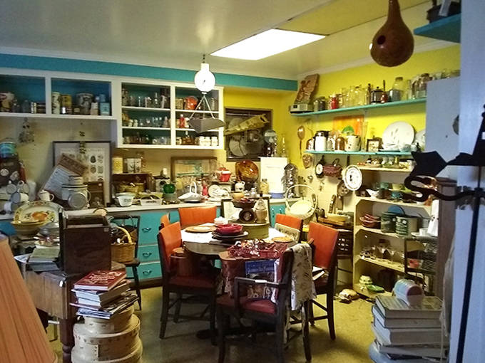 Vintage kitchenware stacked on every available surface creates a delightful chaos that somehow makes perfect sense, like your grandmother's cupboards exploded in the best way.