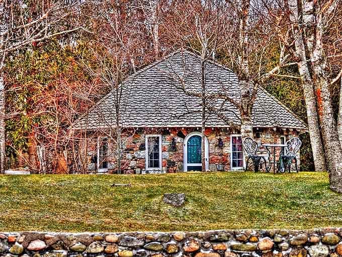 This charming stone cottage seems to whisper stories of generations past, nestled among autumn trees like a storybook illustration.