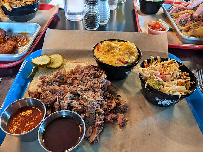 Tender strands of smoke-kissed pork alongside mac and cheese that bubbles with molten promise and coleslaw that cuts the richness.