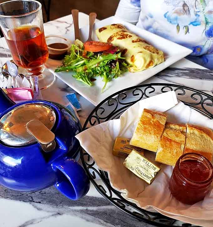 A golden crêpe lounges beside fresh greens and crusty baguette slices – breakfast that makes cereal look like it's not even trying.