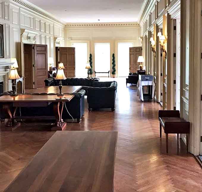 The mansion's elegant seating area whispers of cocktail hours past, when conversations flowed as smoothly as the perfectly polished herringbone floors.