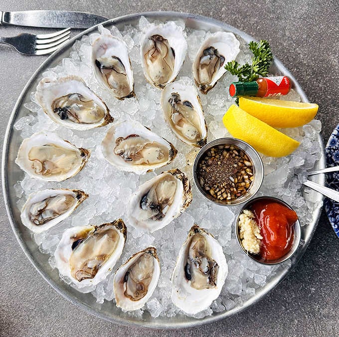 Fresh oysters glisten on ice like briny treasures from the deep, served with classic accompaniments that let their ocean-fresh flavor shine through.
