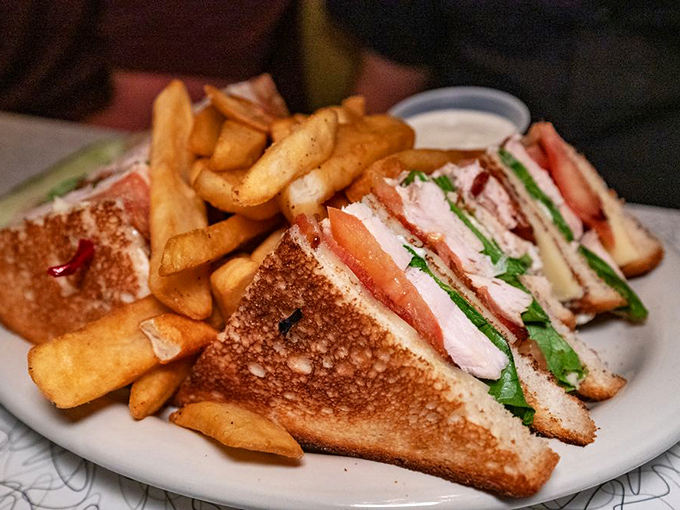 The club sandwich arrives like an architectural marvel &ndash; layers of turkey, bacon, and fresh veggies creating a skyscraper of flavor that demands a strategic approach.