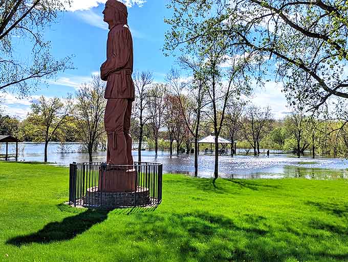 Voyageur Park offers a peaceful riverside retreat where the imposing wooden statue stands watch over waters that have witnessed centuries of history.