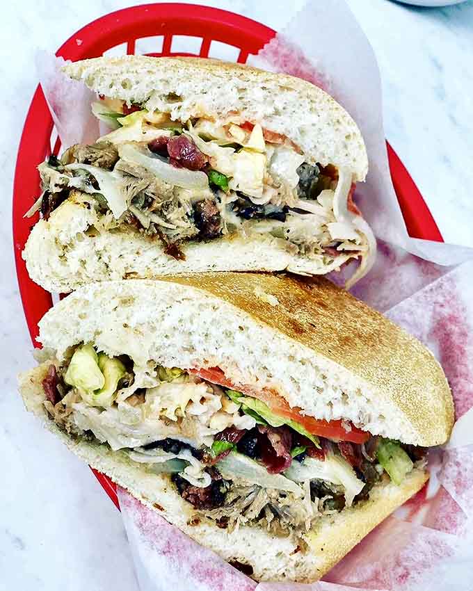 The Yunque Tripleta sandwich &ndash; a skyscraper of meats, cheese, and veggies that requires a game plan before the first bite.