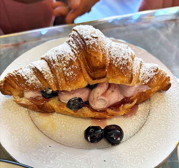 Blueberries burst with flavor in this powdered sugar-dusted croissant, creating a perfect balance of tartness and creamy indulgence.