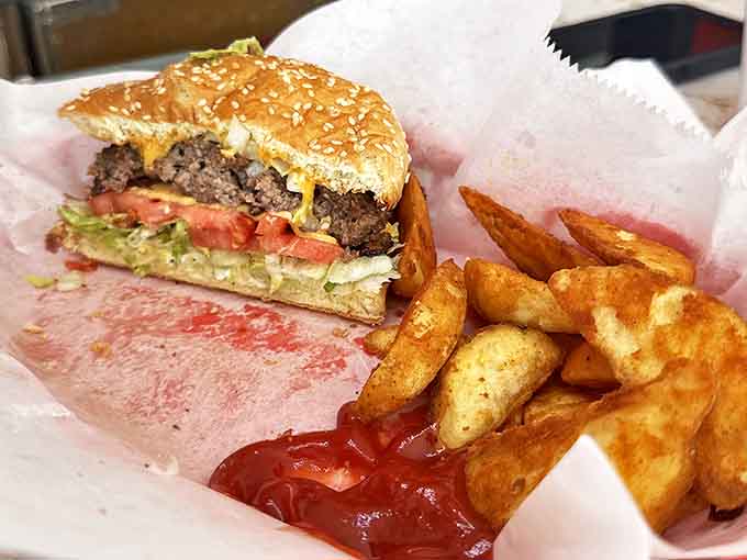 The perfect pairing: a cheese-draped burger alongside golden potato wedges that achieve the ideal balance of crispy exterior and fluffy interior.