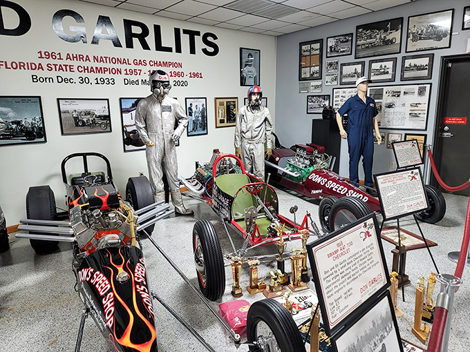 Don Garlits' legendary racing suits stand guard over his pioneering dragsters, a testament to an era when fire-resistant clothing was as innovative as the cars themselves.