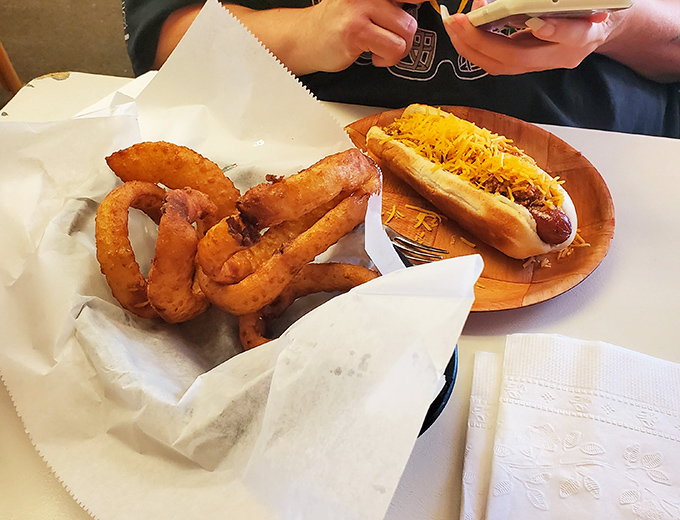 The holy trinity: a perfectly dressed coney, golden onion rings, and a side that proves why "fresh-cut fries" deserves top billing on the sign.