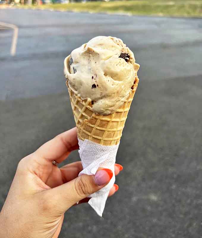 A hand-packed cone of what appears to be cookie-studded ice cream stands ready for its close-up before meeting its delicious destiny.