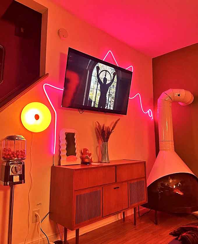 The living area features a fireplace that doesn't just warm the room &ndash; it makes a statement with neon accents that turn even Tuesday nights into special occasions.