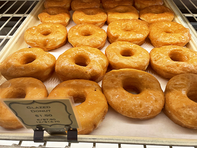 Golden-hued donuts glisten under bakery lights, their perfect glaze catching the morning sun like edible jewels.