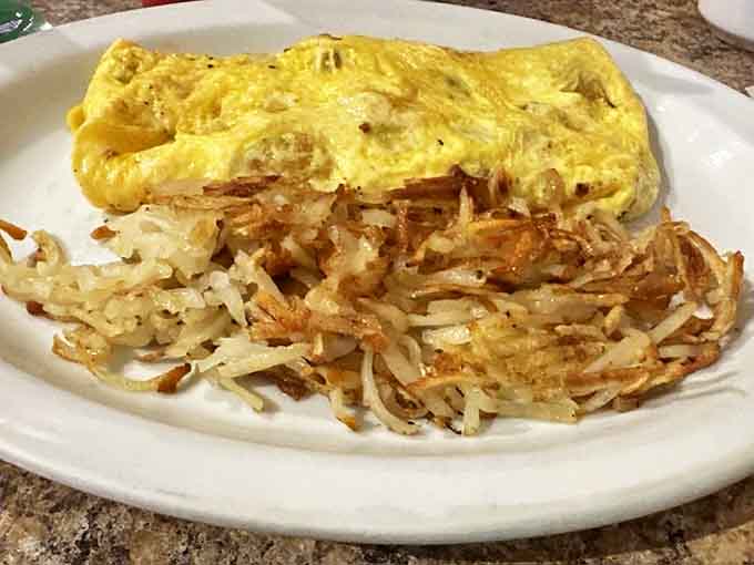 A fluffy yellow pillow of egg perfection alongside hash browns so perfectly executed they deserve their own fan club.