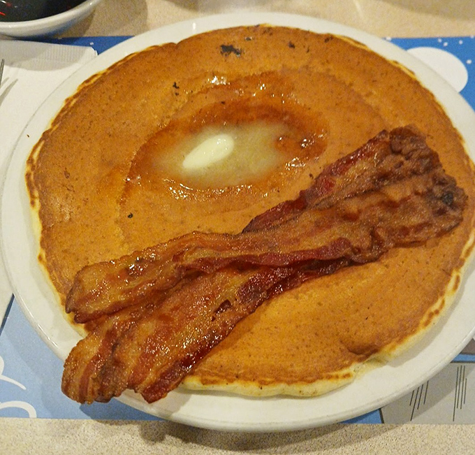 Breakfast architecture at its finest: a golden pancake throne for melting butter, with crispy bacon sentinels standing guard. 