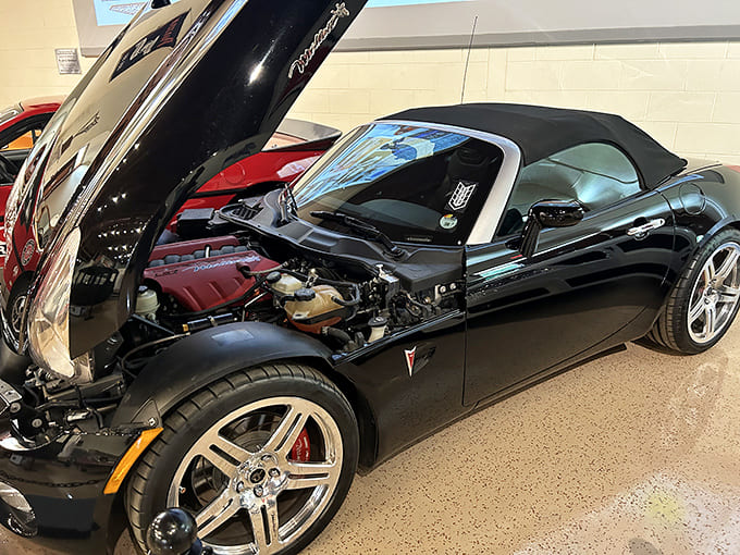 The Pontiac Solstice with its hood up reveals the mechanical heart that made driving an actual experience, not just transportation.
