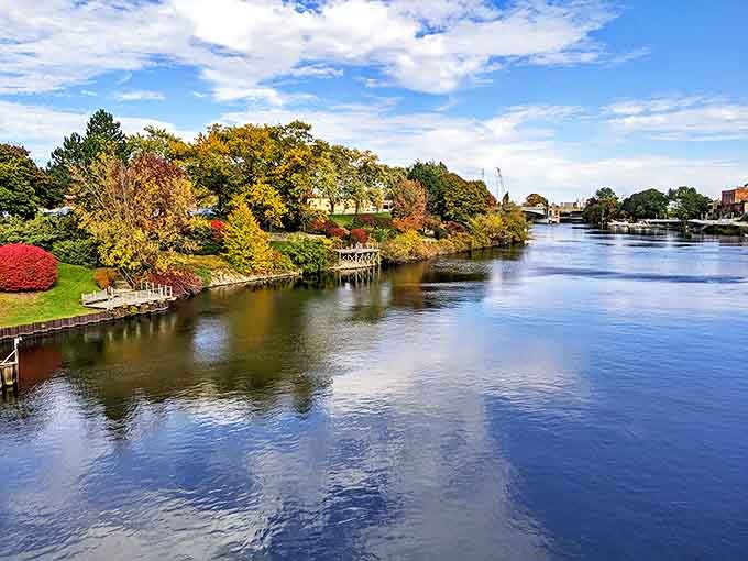 The Manistee River reflects autumn's glory, creating a double showing of nature's most spectacular seasonal performance.