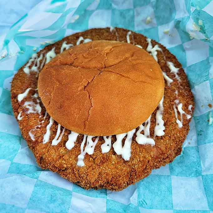 The giant pork tenderloin sandwich laughs at the concept of bun-to-meat ratio, extending gloriously beyond all reasonable boundaries.