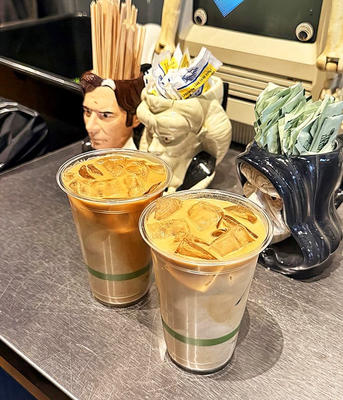 Iced lattes sit ready for sipping, flanked by quirky figurine holders that add a playful touch to your caffeine fix.