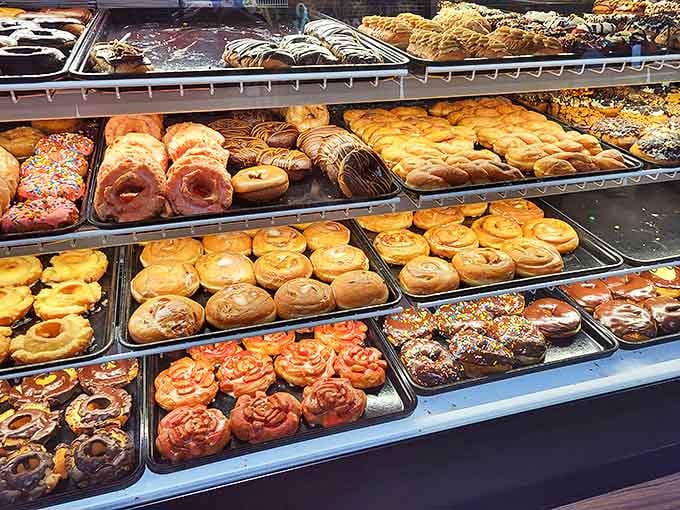 The display case stretches like a museum of sugary masterpieces, each tray more tempting than the last.