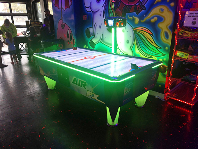The air hockey table glows with electric anticipation, ready for the satisfying clack of puck against paddle in this timeless arcade staple.