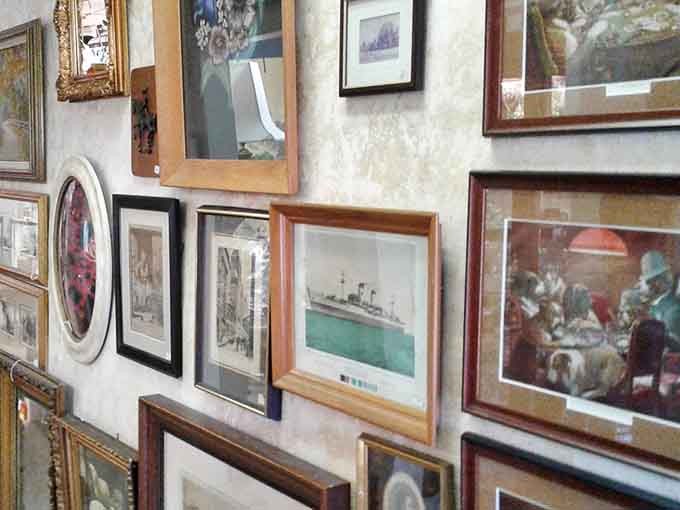 The wall of vintage frames creates an artistic tapestry of history, each frame having once showcased someone's cherished memories or prized artwork.