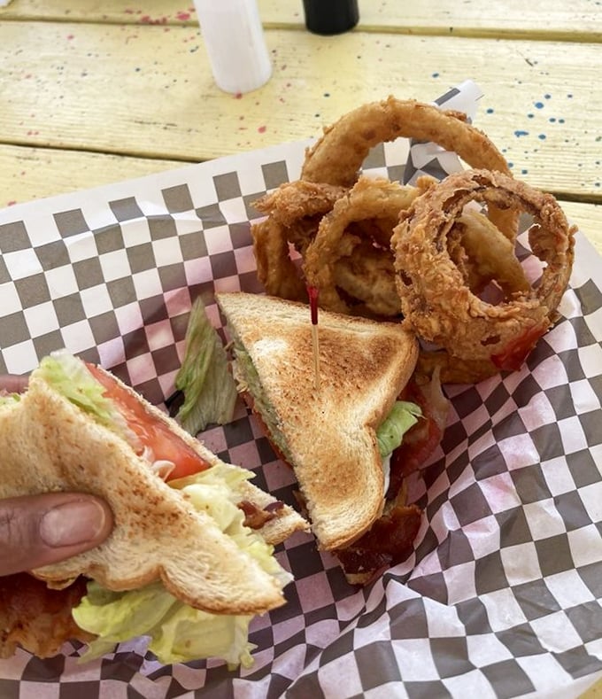 A club sandwich so generously stacked it requires structural engineering to eat properly, served with onion rings that could win awards if awards were given for such magnificent things.